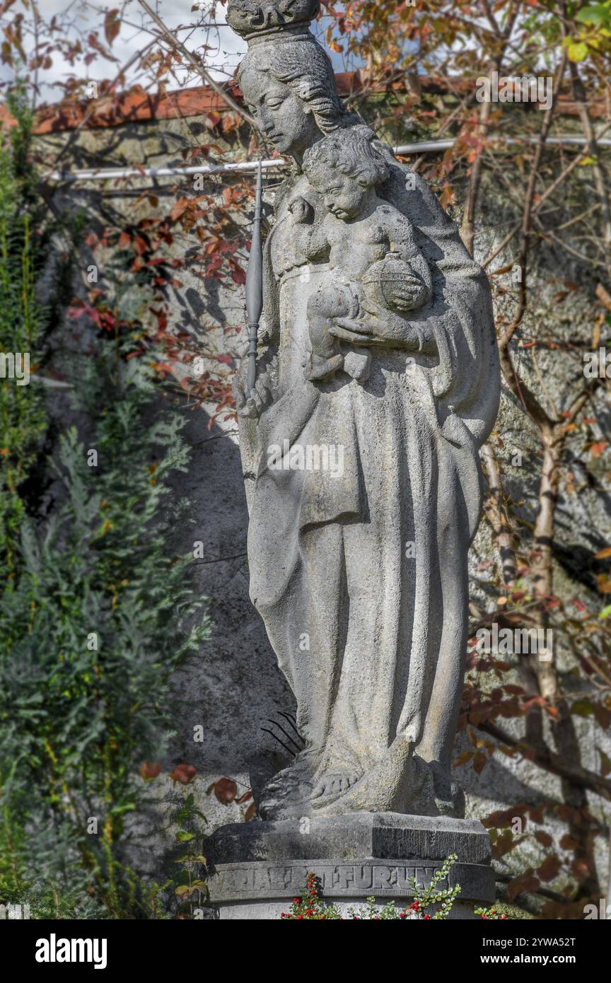 Stone statue of the Virgin Mary with baby Jesus near the rococo church ...
