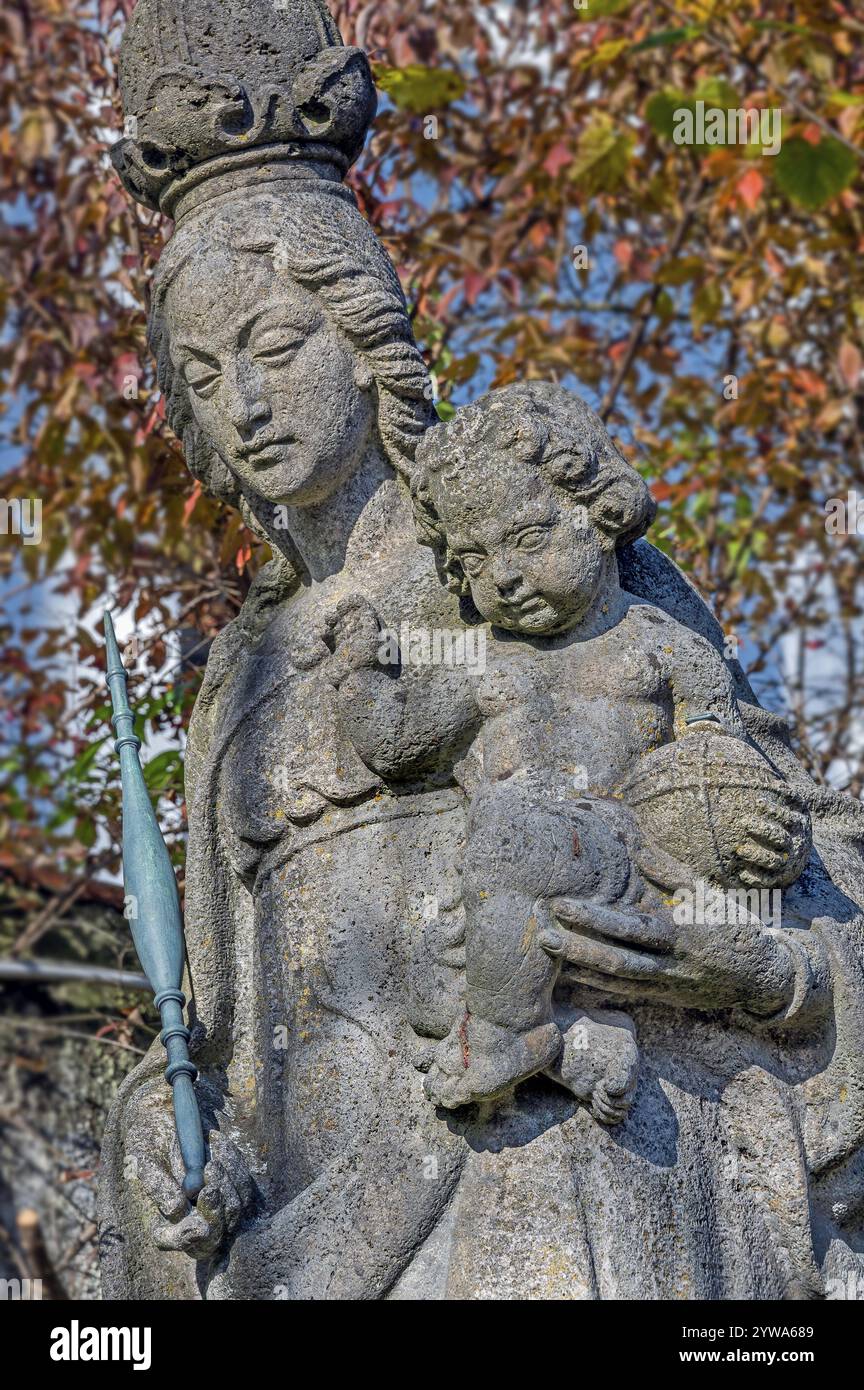 Stone statue of the Virgin Mary with baby Jesus near the rococo church ...