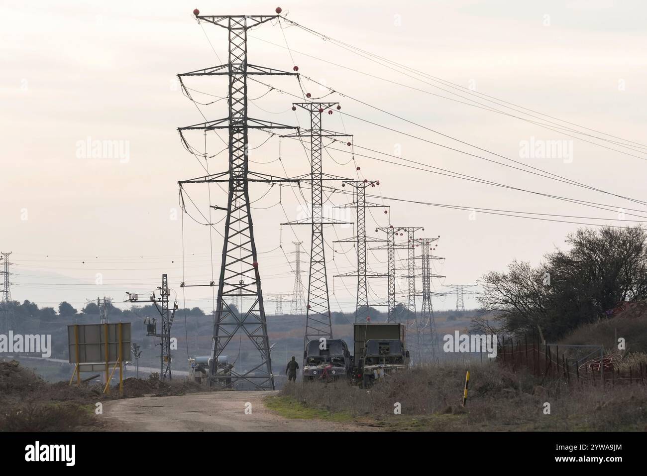 An Israeli soldier walks next to armored vehicles near the so-called ...