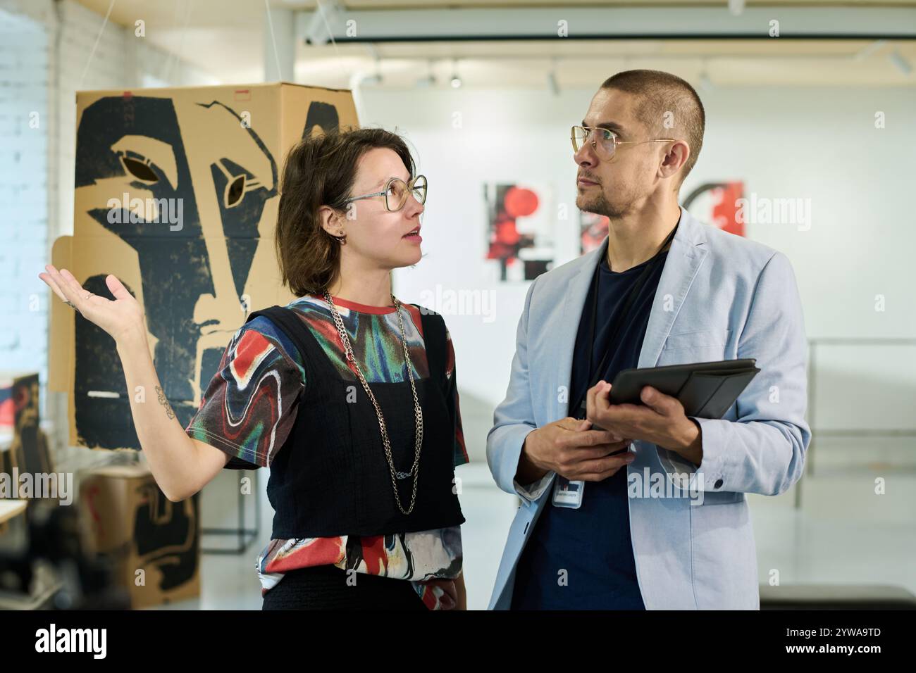 Creative artist talking to gallery manager while helping him prepare ...