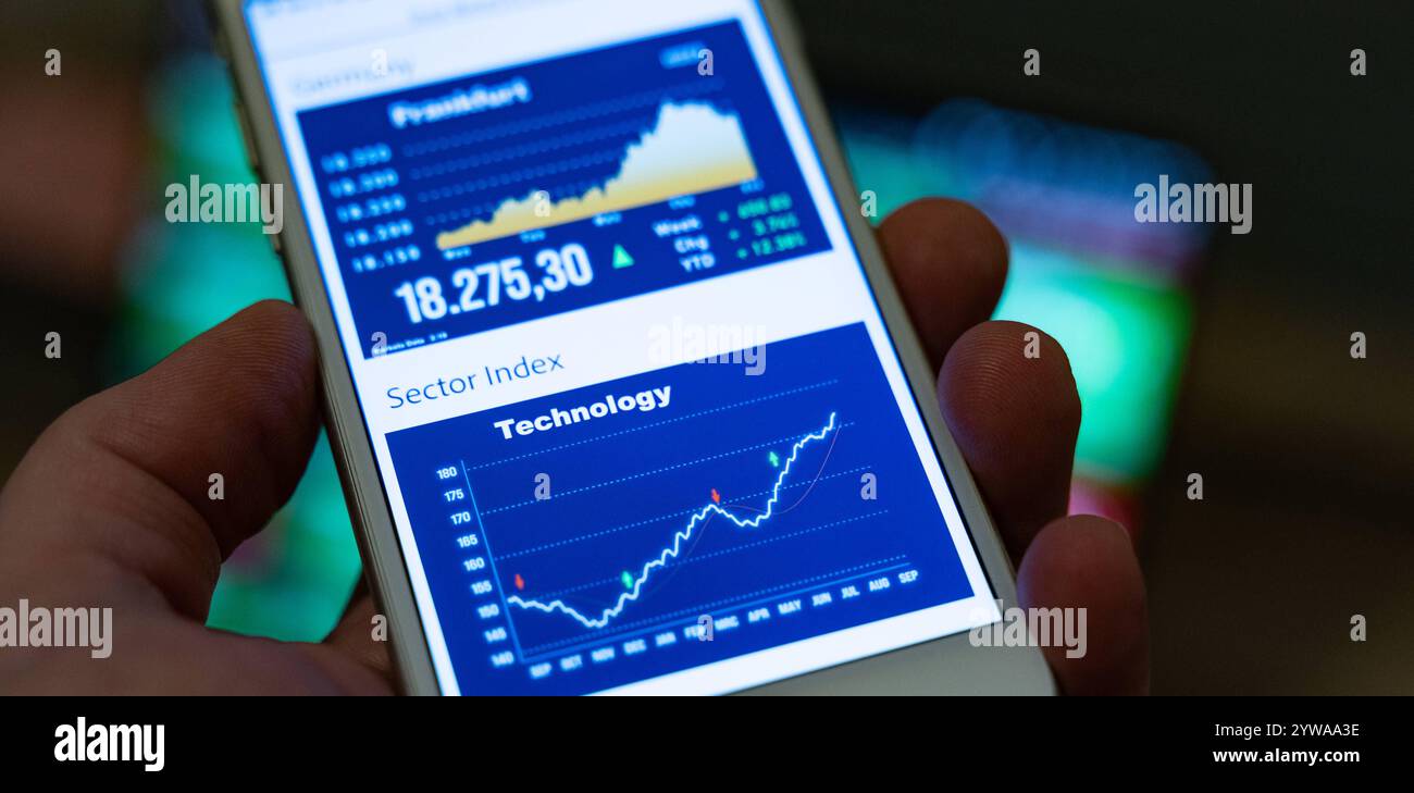 Hand holds a smartphone which shows a rising technology stock index ...