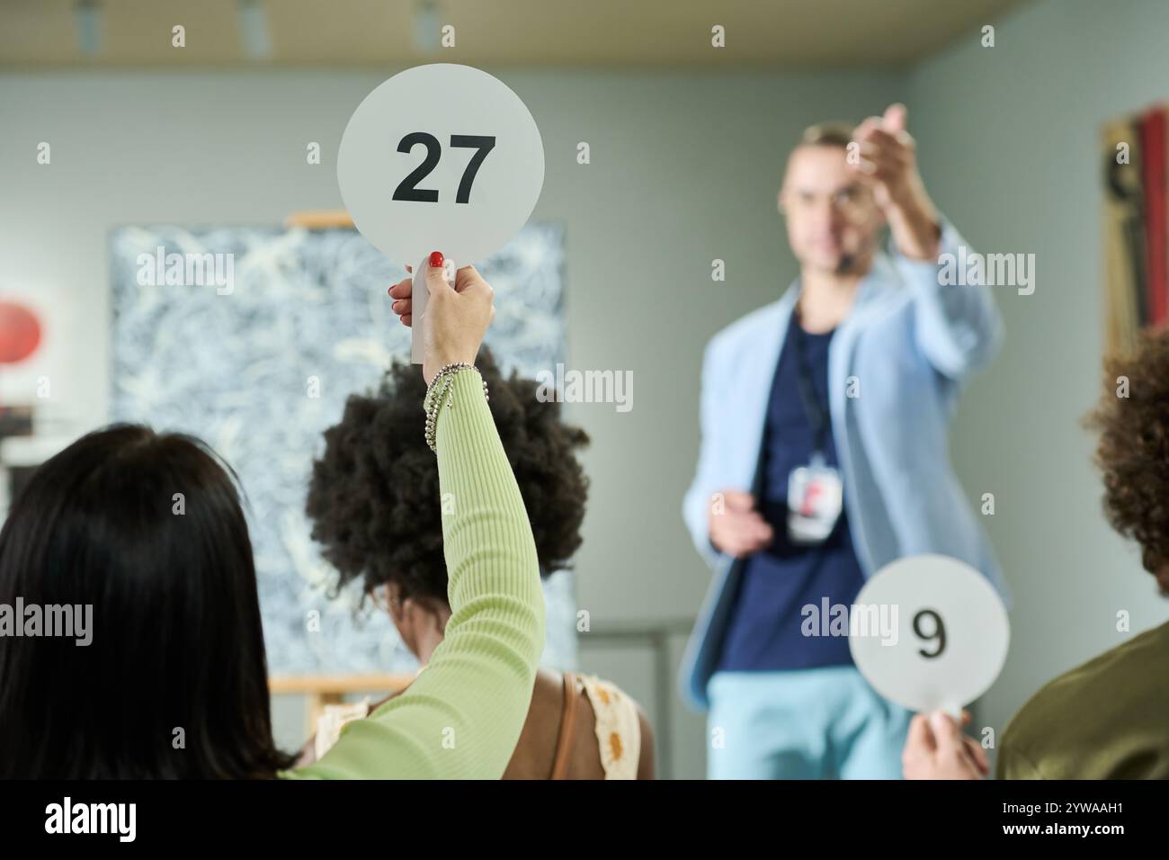 Rear view of young brunette woman raising hand holding paddle with ...