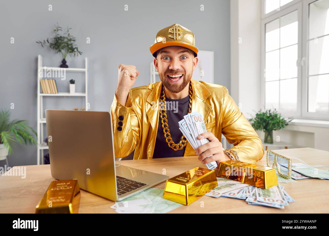 Funny excited man sitting at desk holding money cash of dollar bills ...