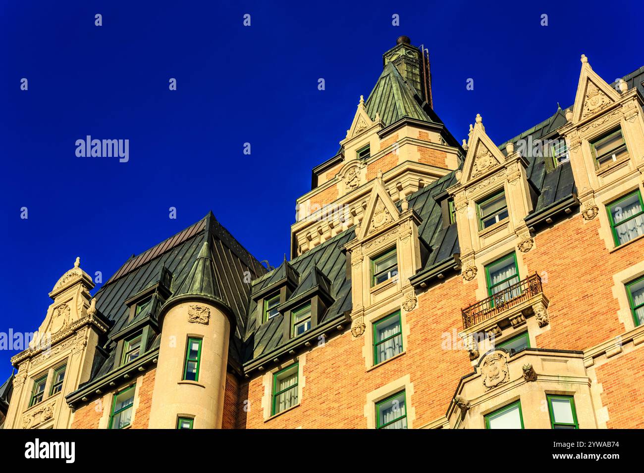 A large brick building with a green roof and a clock tower. The ...