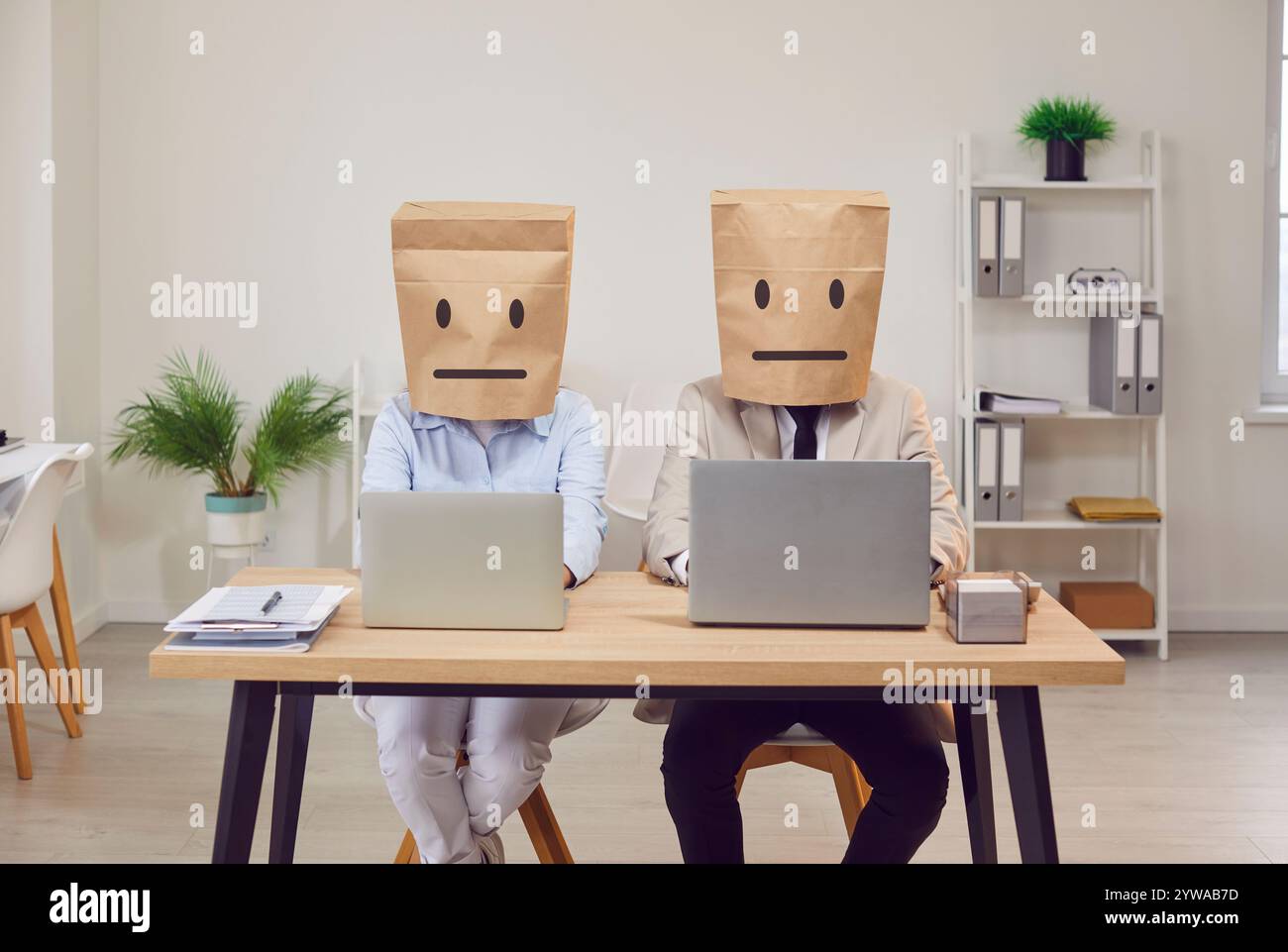 Company employees in paper bags on head with drawn upset faces sitting ...