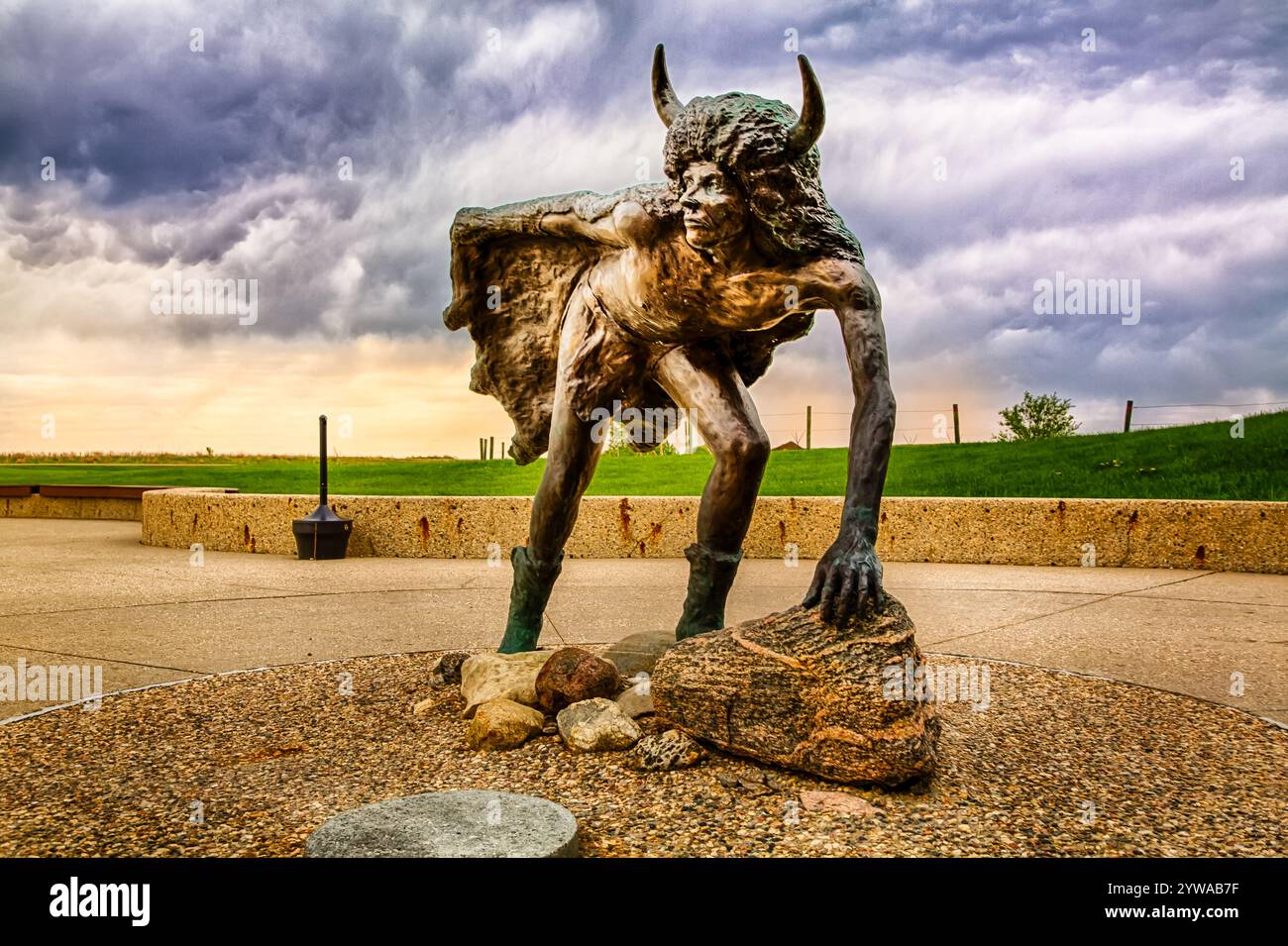 A statue of a man with horns and a cape is standing on a rock. The ...