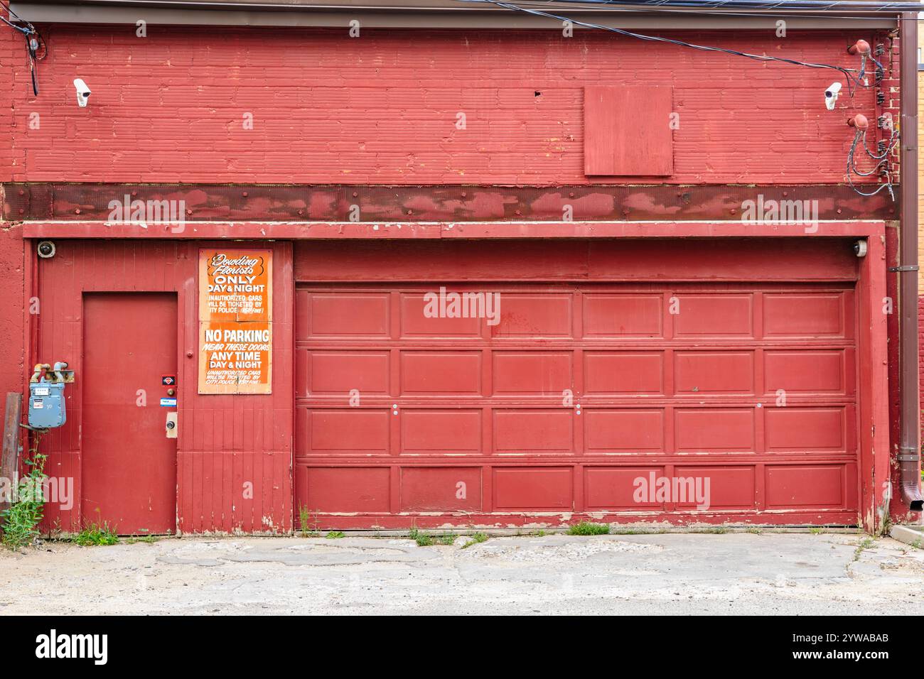 A red garage door with a sign on it that says no parking. The garage is ...
