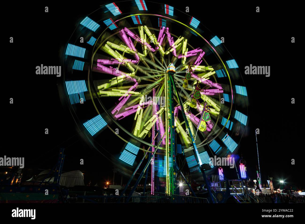 A colorful merry go round with lights on it. The lights are green ...