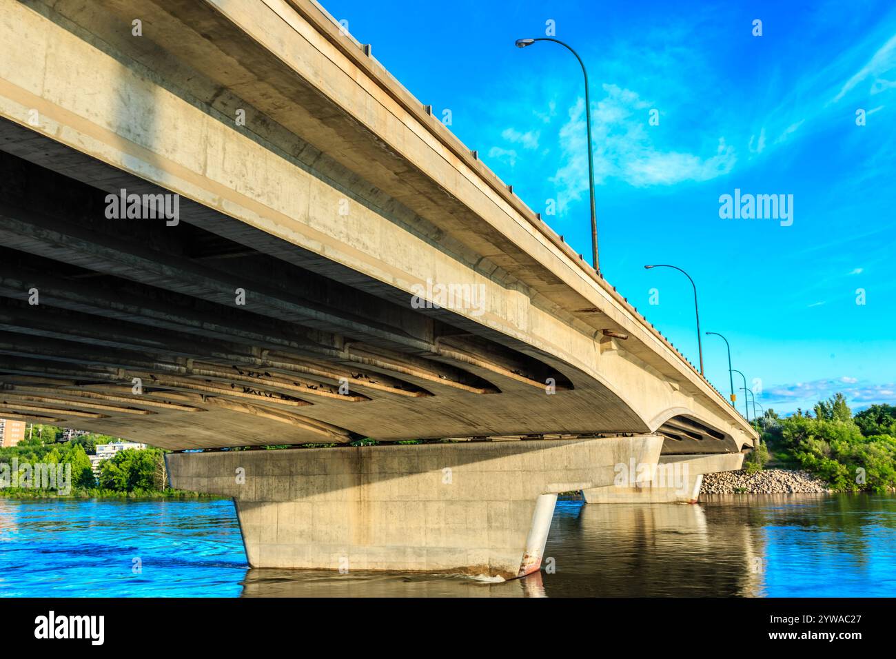 A bridge spans a river with a clear blue sky above. The bridge is made ...