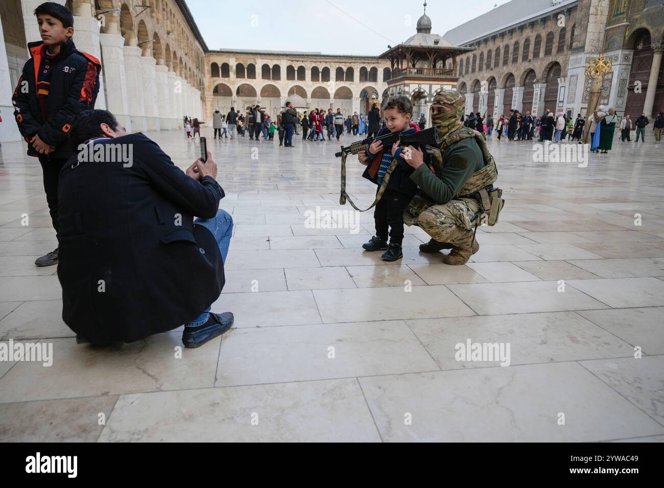 A boy poses for a photo with a masked Hayat Tahrir al-Sham (HTS ...