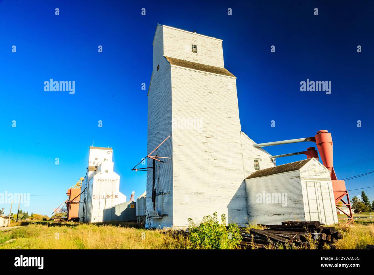 A large white grain silo is surrounded by other silos. The sky is blue ...