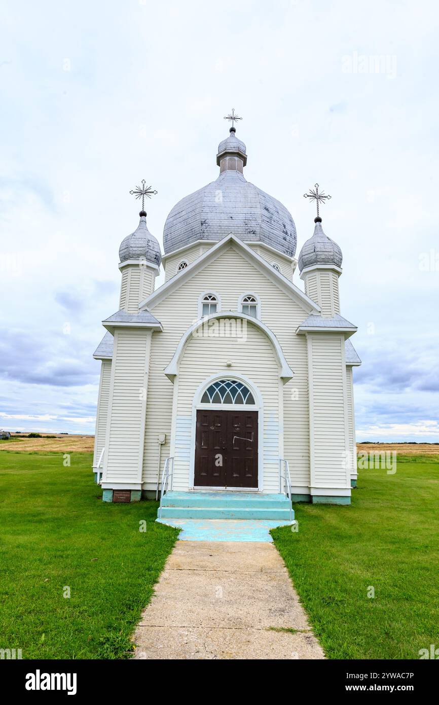 A small white church with a steeple and a cross on top. The church is ...