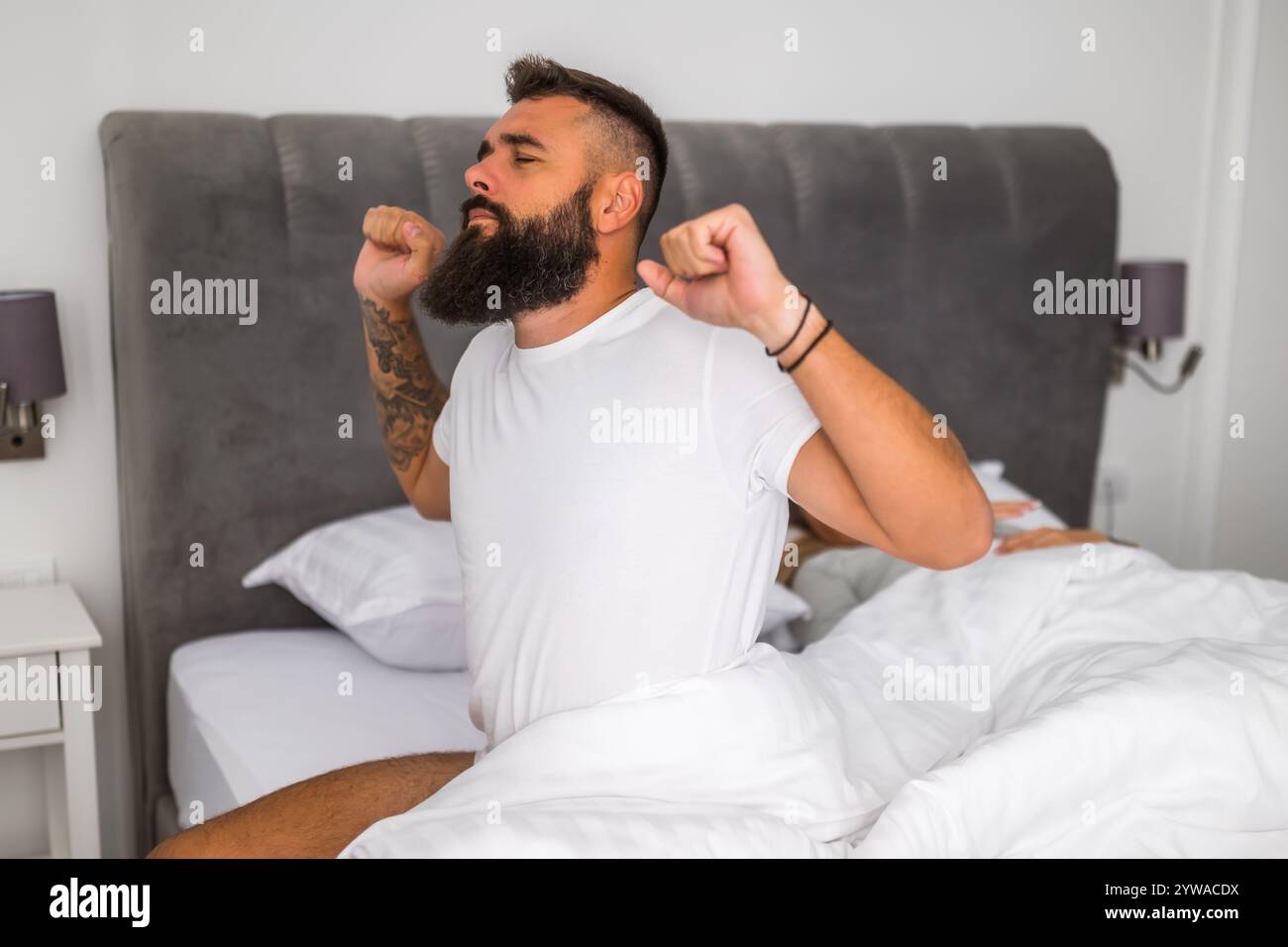 Young couple is sleeping in bed. Man is waking up for work Stock Photo ...