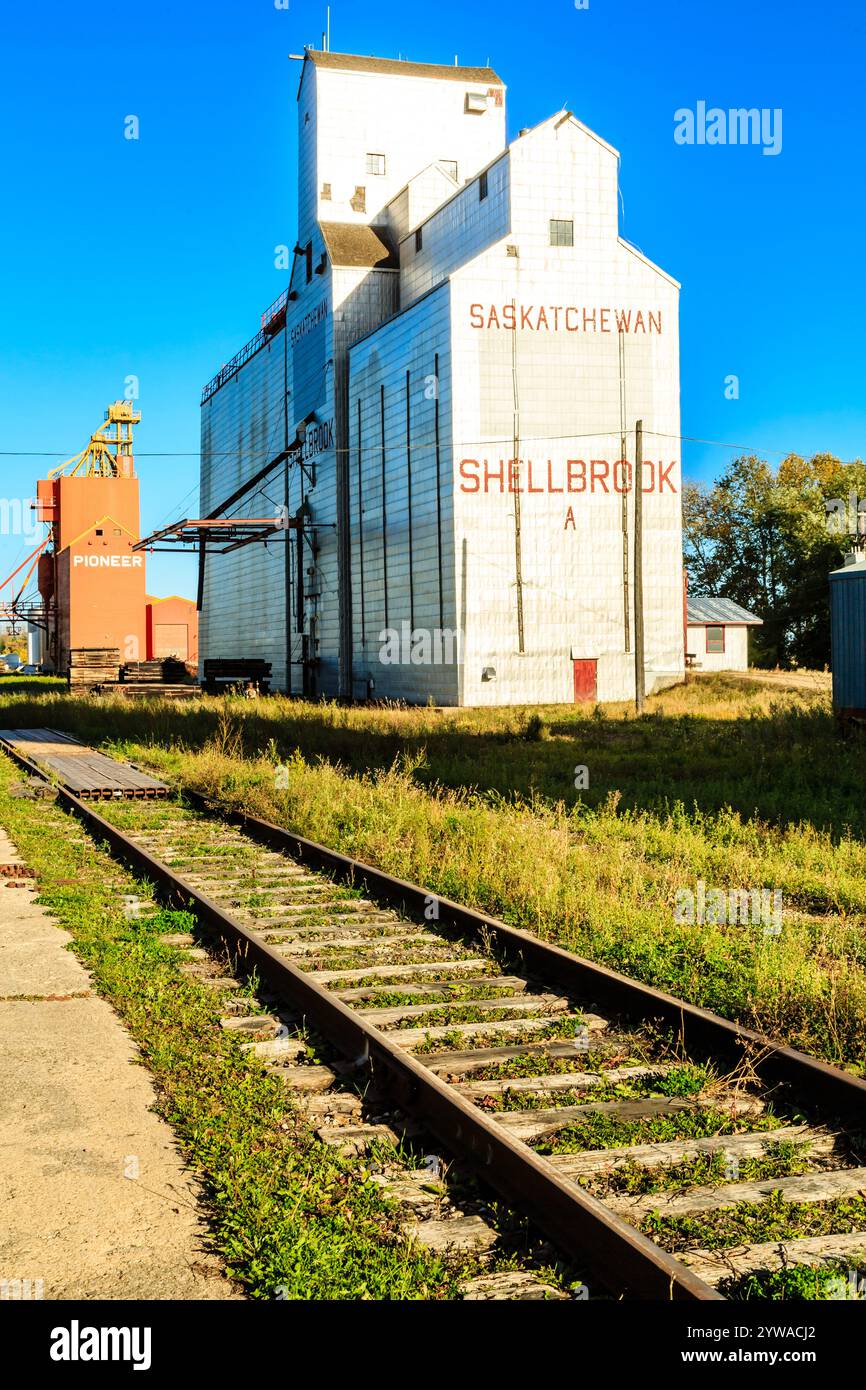 A train tracks lead to a large grain silo. The silo is named Shellbrook ...