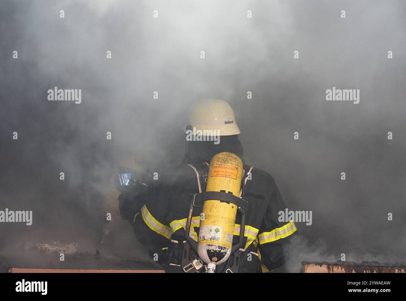 Hamburg, Germany. 10th Dec, 2024. A firefighter uses a measuring device ...