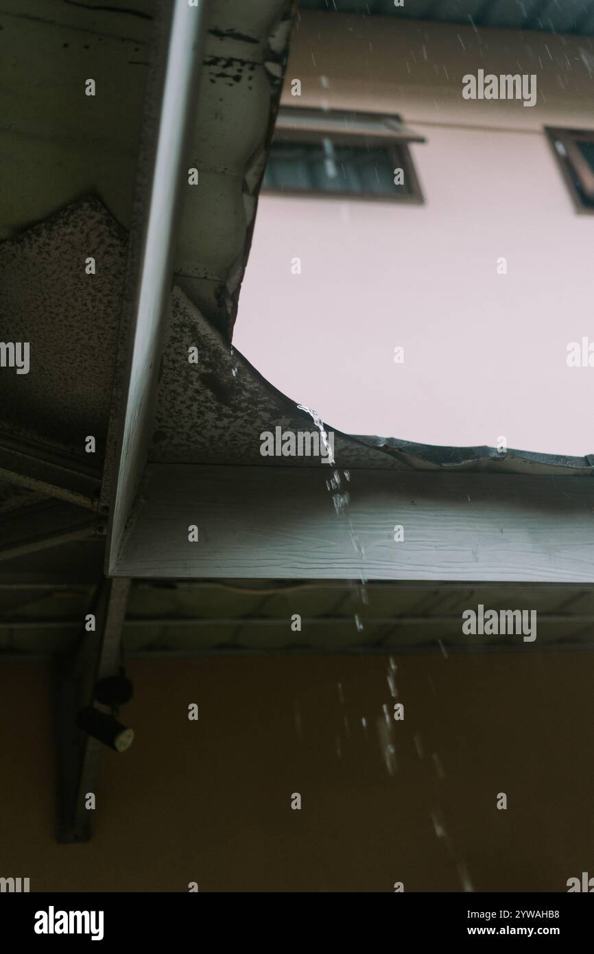 Raindrops falling from the edge of a roof tile, captured mid-drop ...