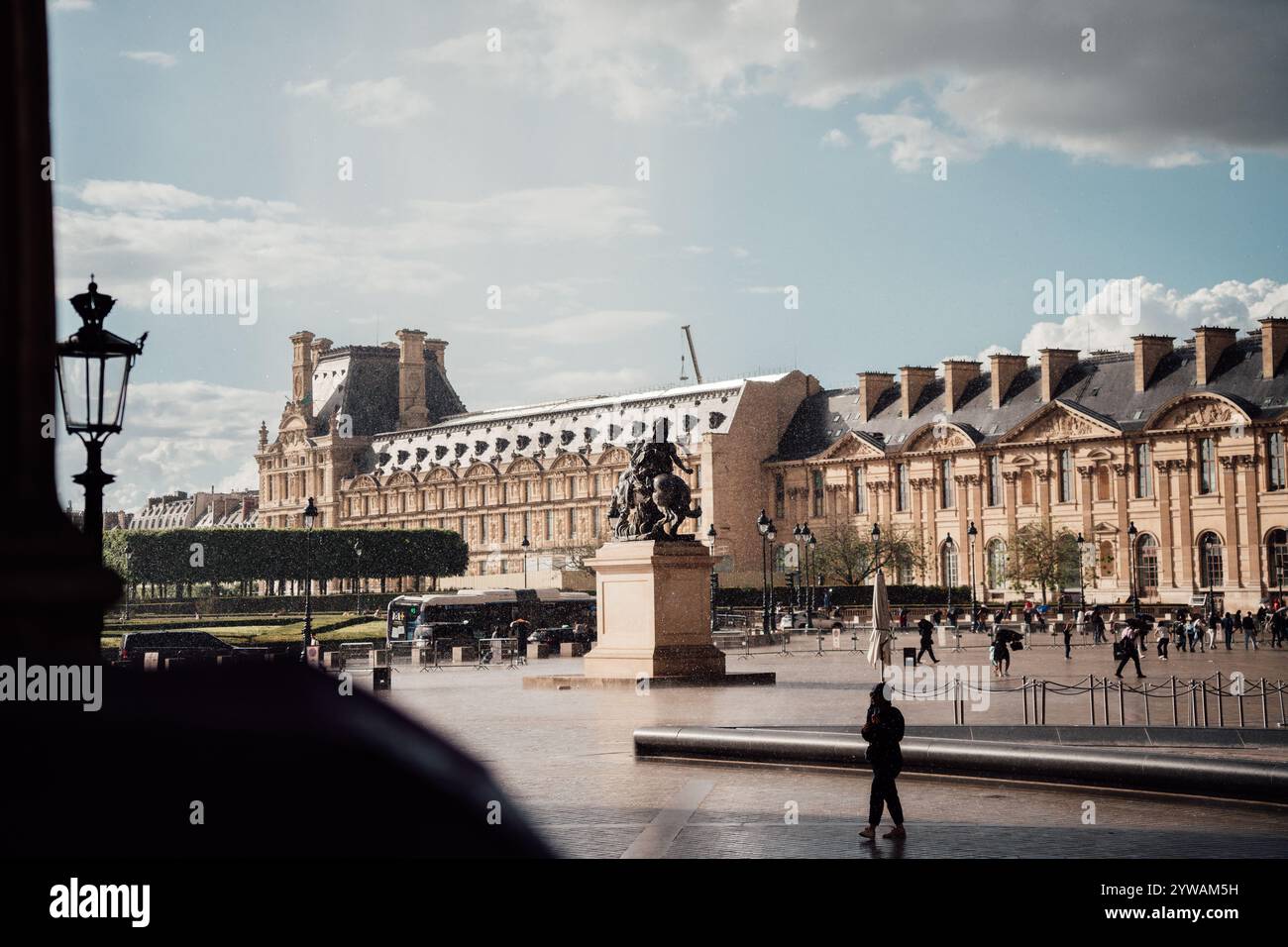 Louvre pyramid under the sun with the ground wet after a day of rain ...