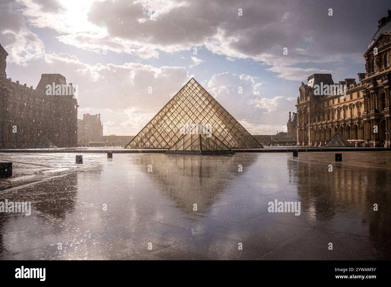 Louvre pyramid under the sun with the ground wet after a day of rain ...