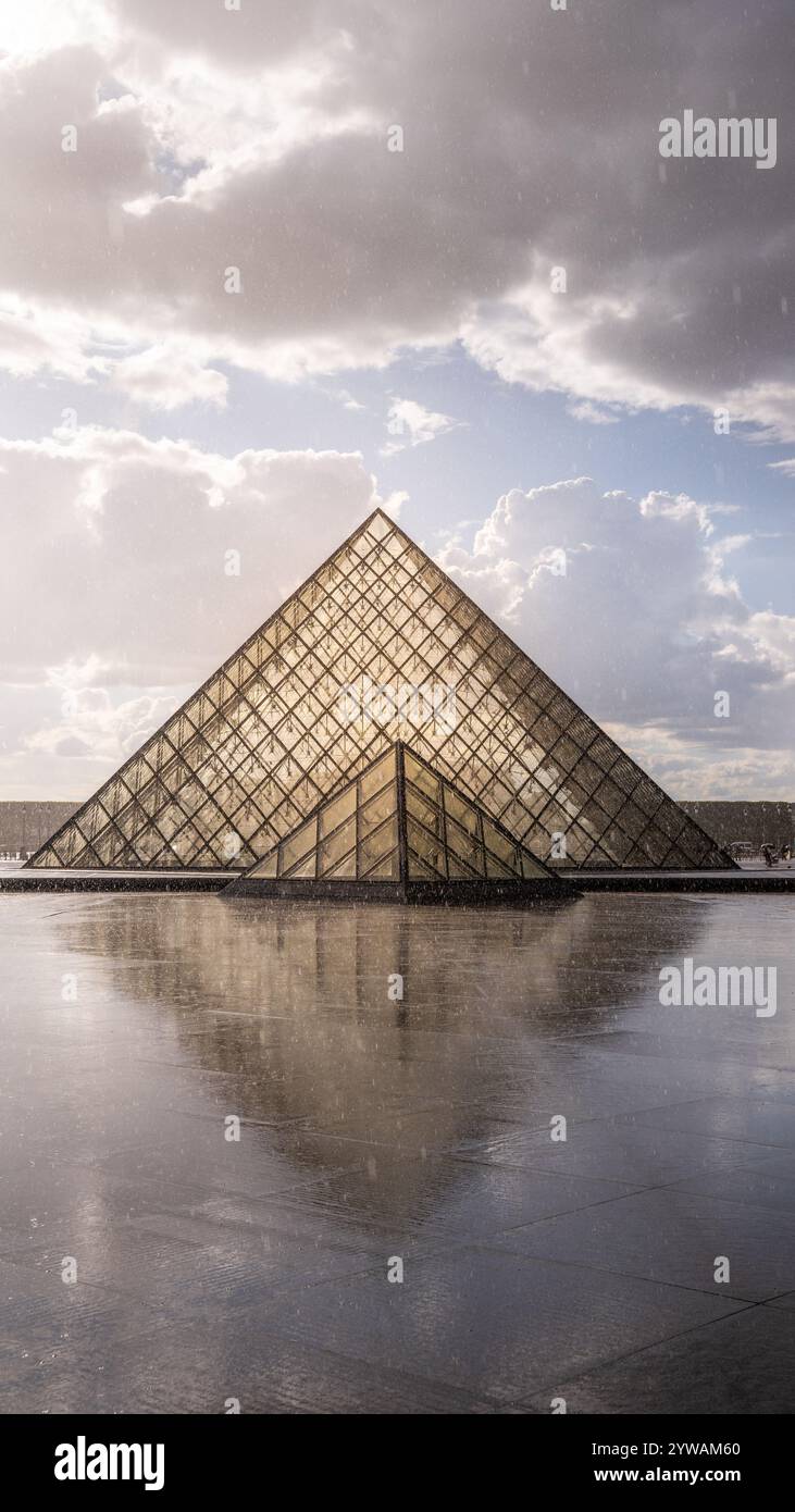 Louvre pyramid under the sun with the ground wet after a day of rain ...