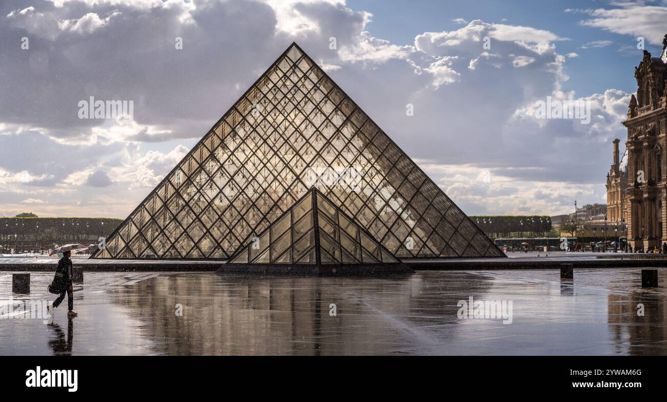 Louvre pyramid under the sun with the ground wet after a day of rain ...
