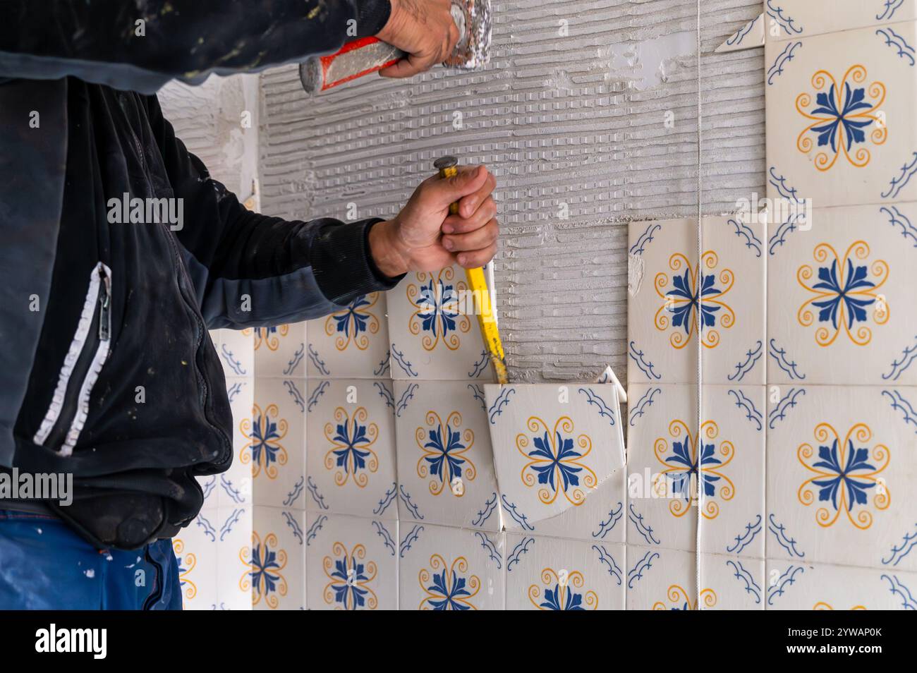 Construction worker removing old tiles with chisel and hammer during ...
