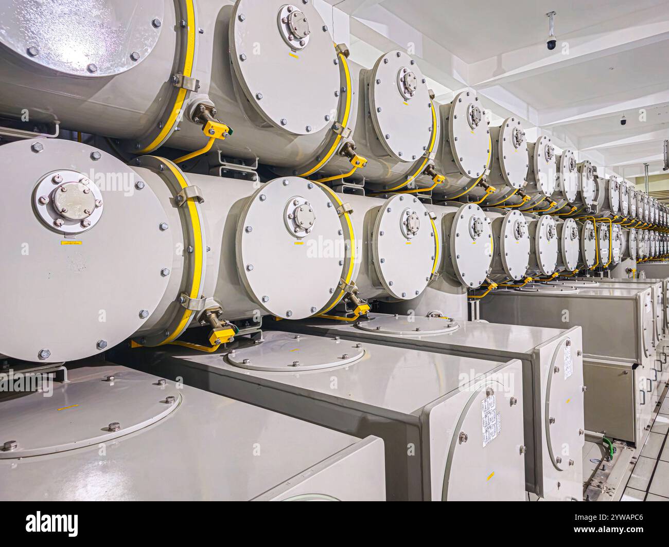A row of white tanks with yellow caps. The tanks are stacked on top of ...