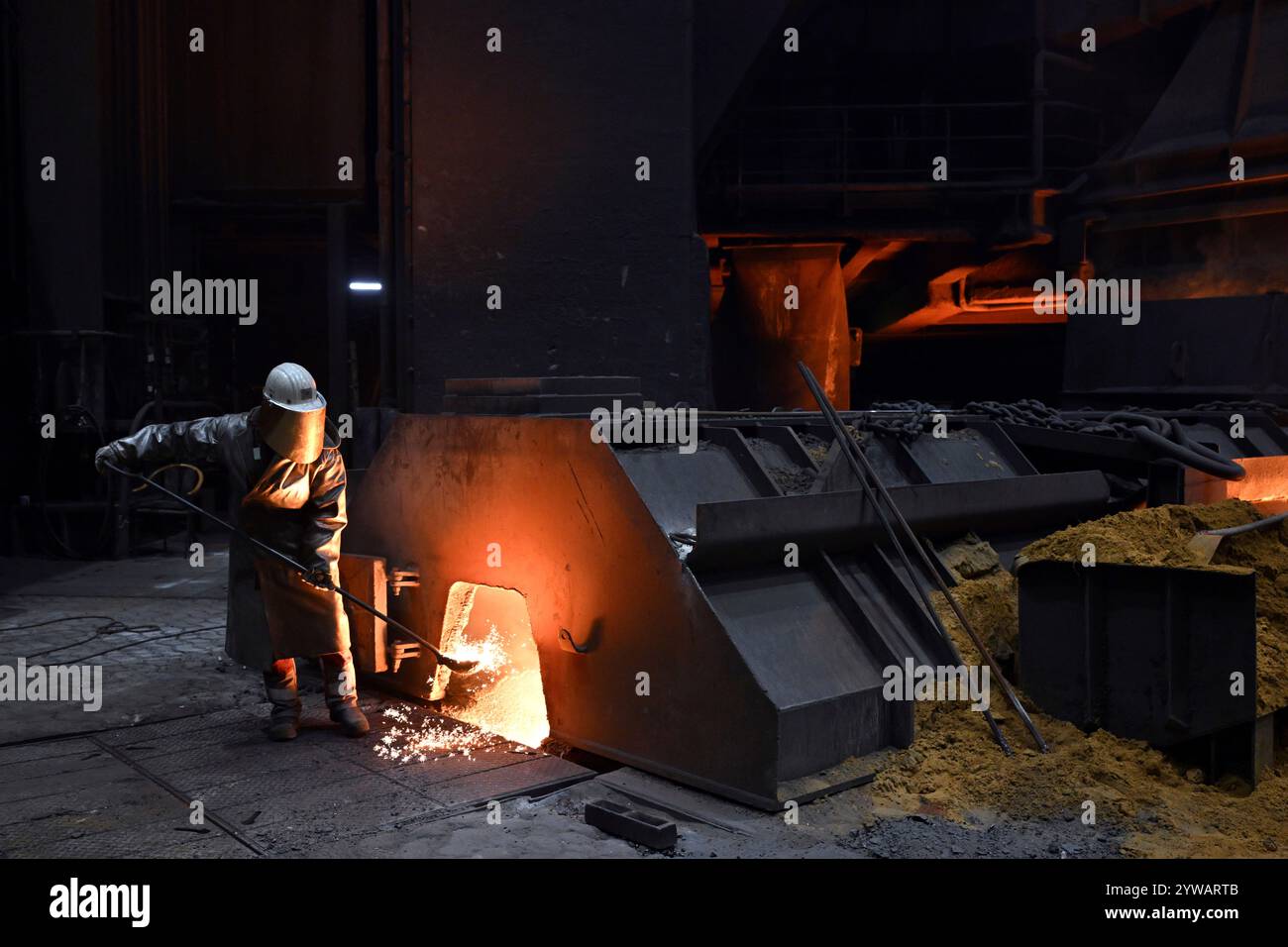 A worker takes a sample of molten pig iron at a blast furnace, at the ...
