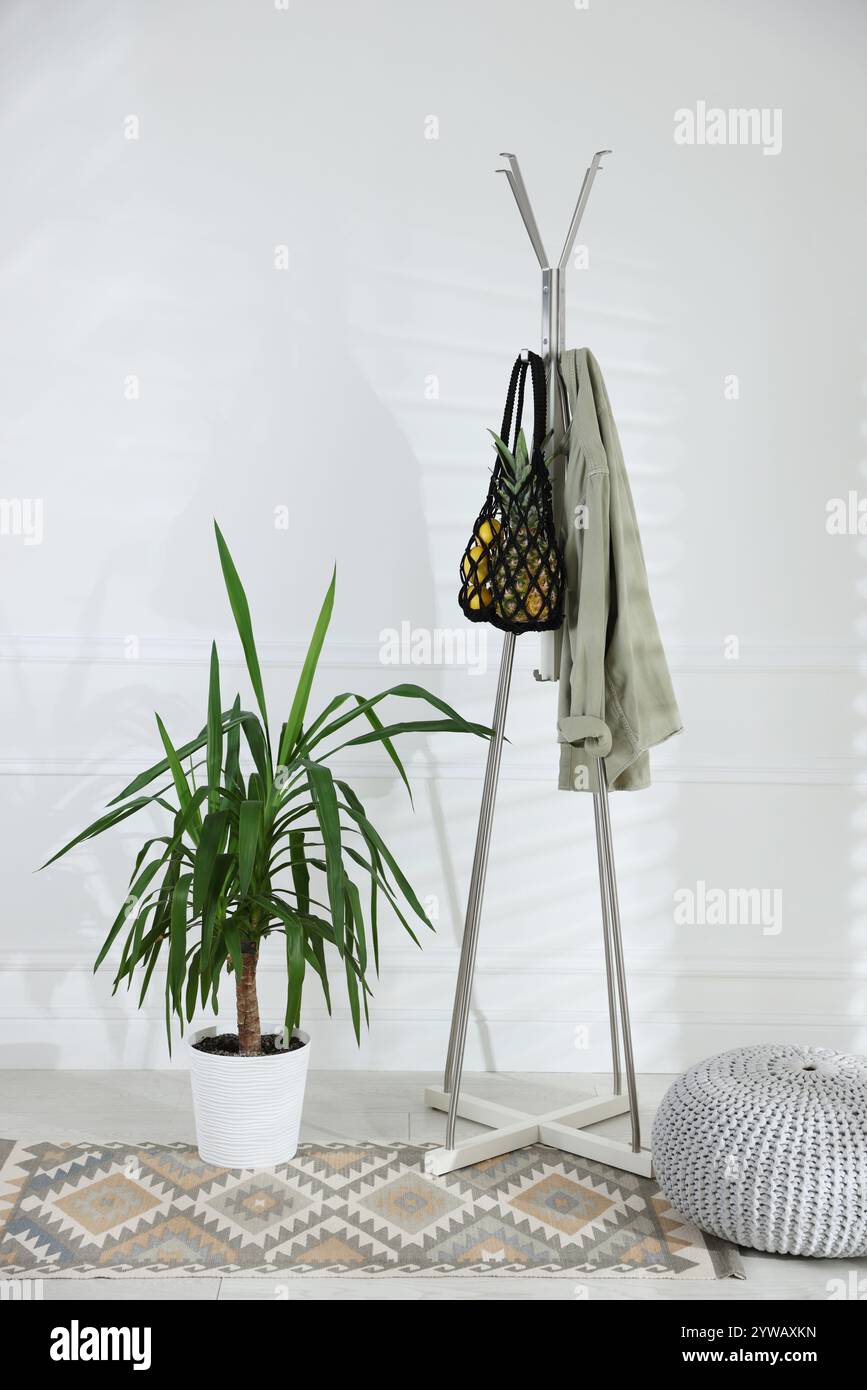 Macrame bag with fruits and jacket on clothing rack indoors Stock Photo ...