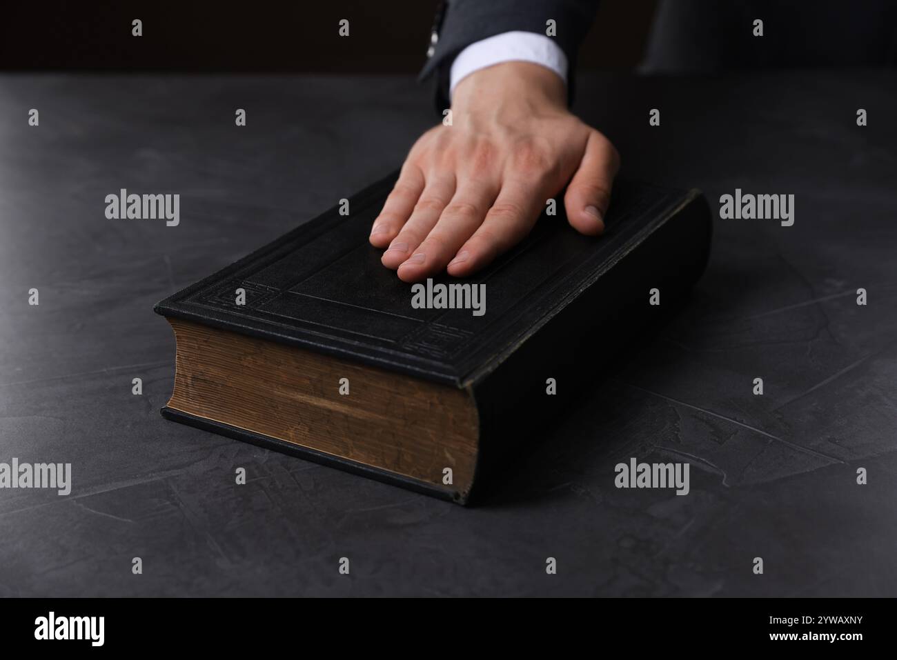 Man taking oath with his hand on Bible at black table, closeup Stock ...