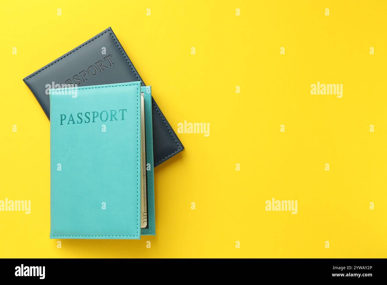 Passports in color covers on yellow background, top view. Space for ...