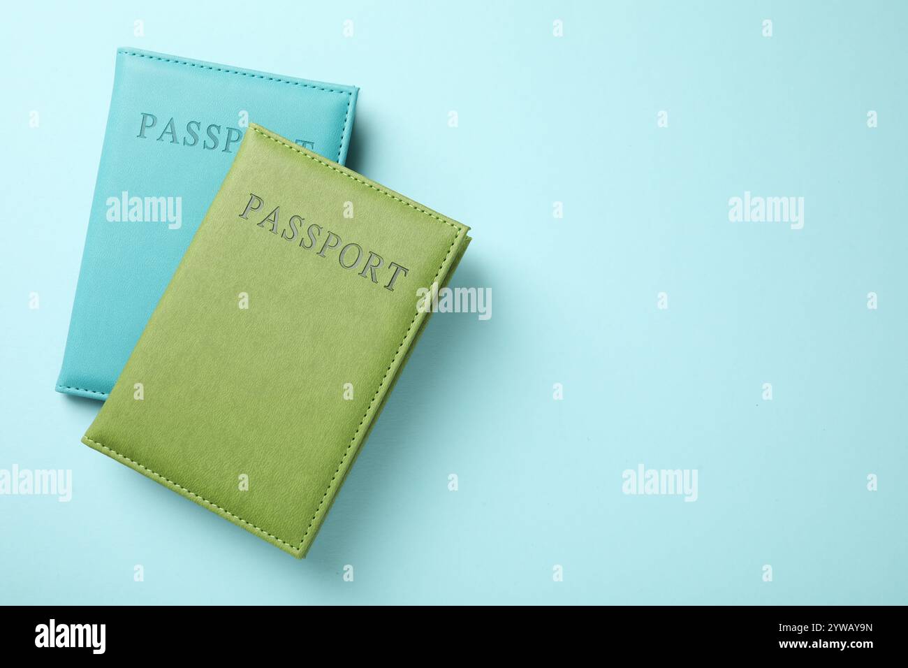 Passports in color covers on light blue background, top view. Space for ...