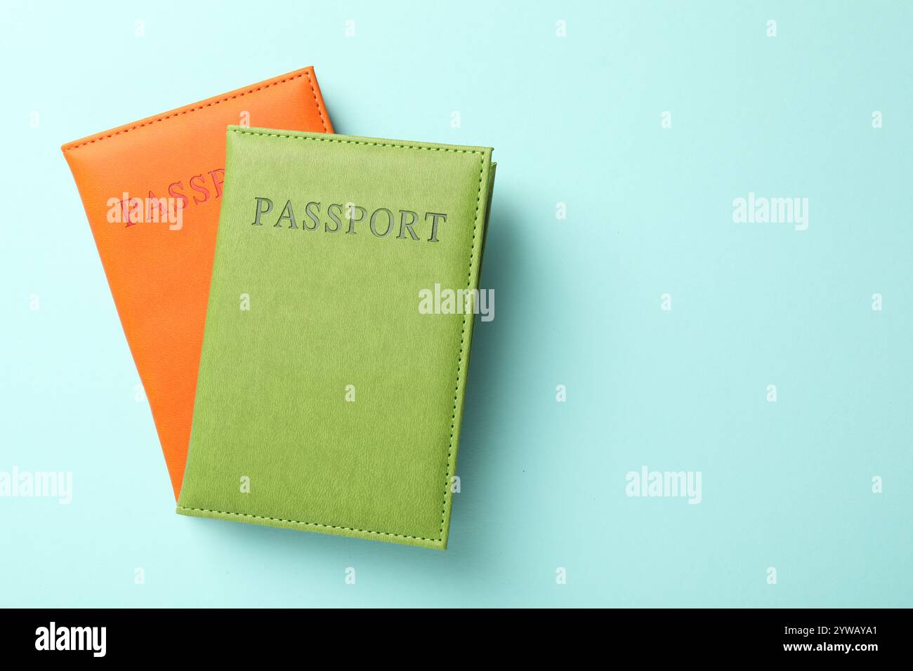 Passports in color covers on light blue background, top view. Space for ...