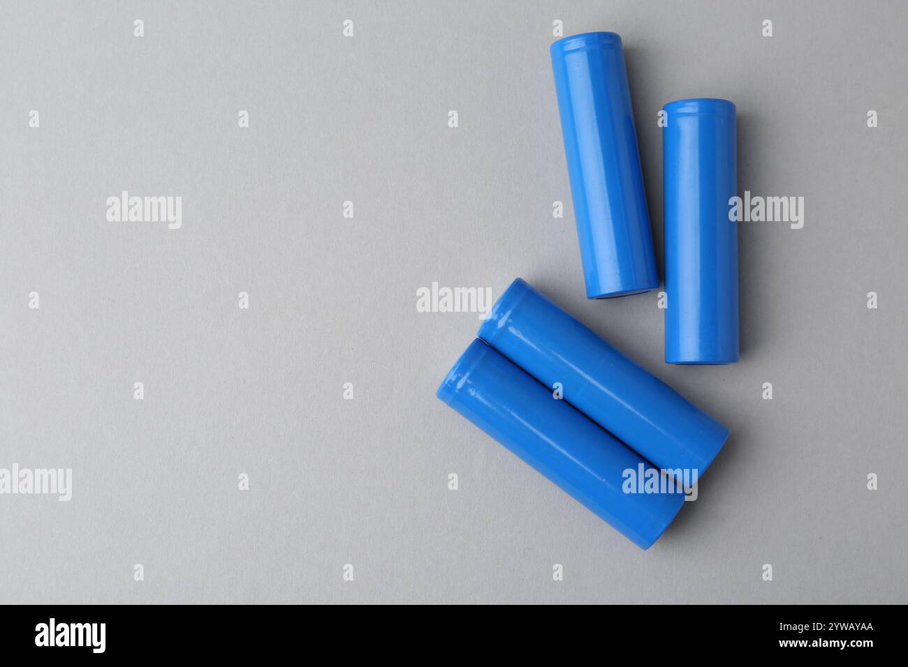 Many AA cell batteries on light grey background, top view. Space for ...