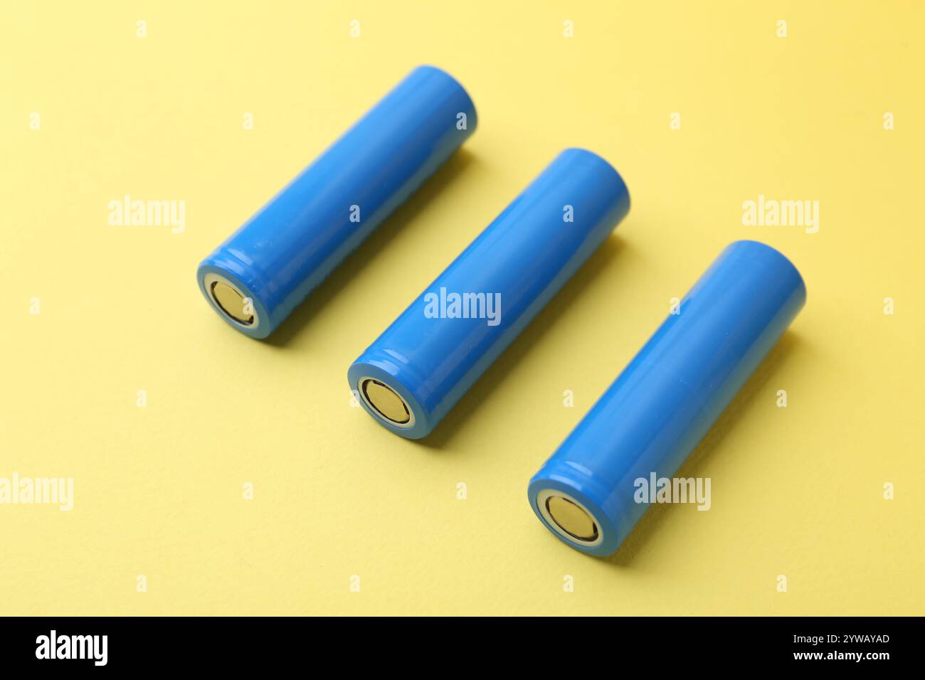 Three AA cell batteries on yellow background, closeup Stock Photo - Alamy