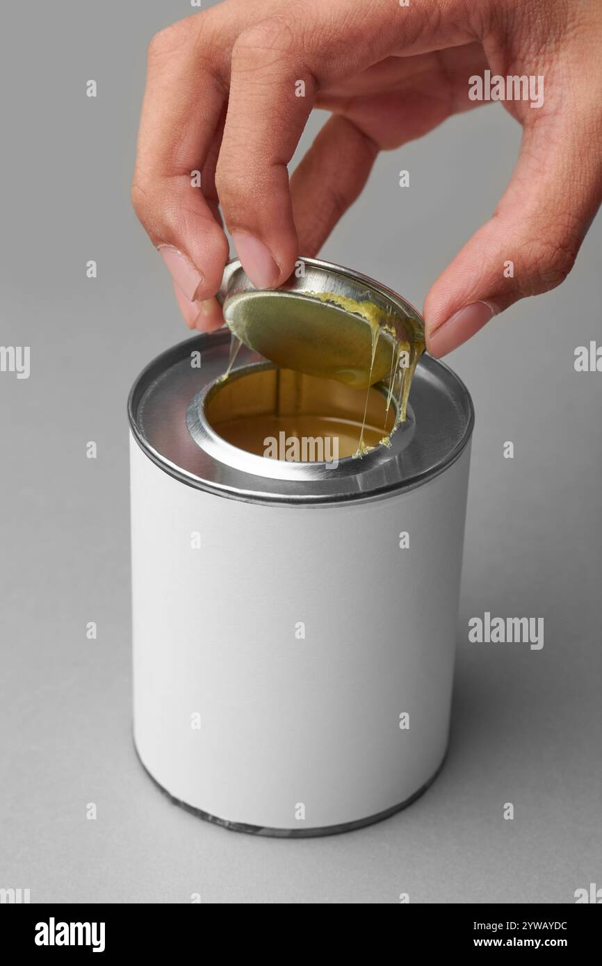 hand opening yellow adhesive in silver tin can isolated gray background ...
