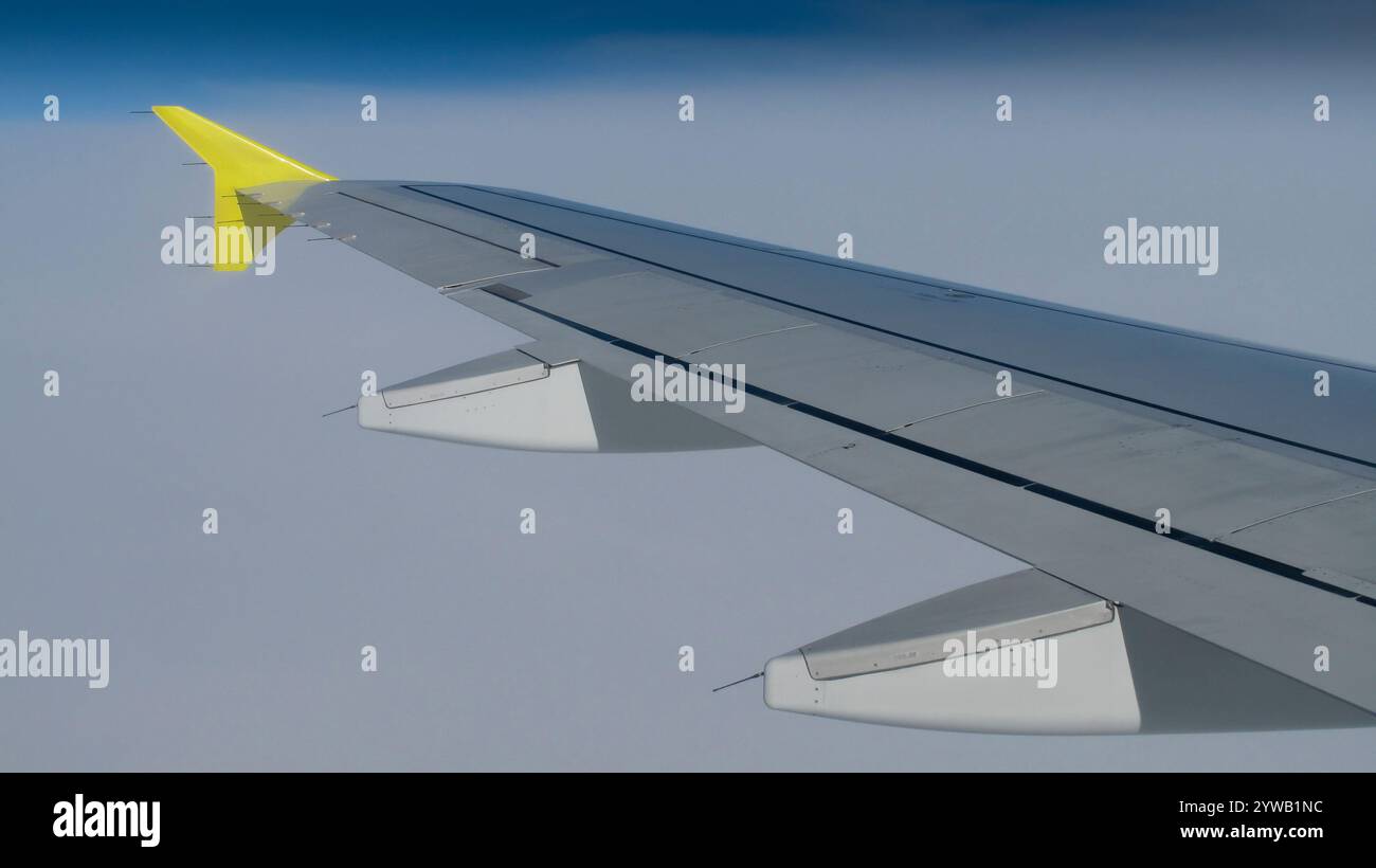 Left wing of a commercial aircraft flying over compact clouds in Europe ...
