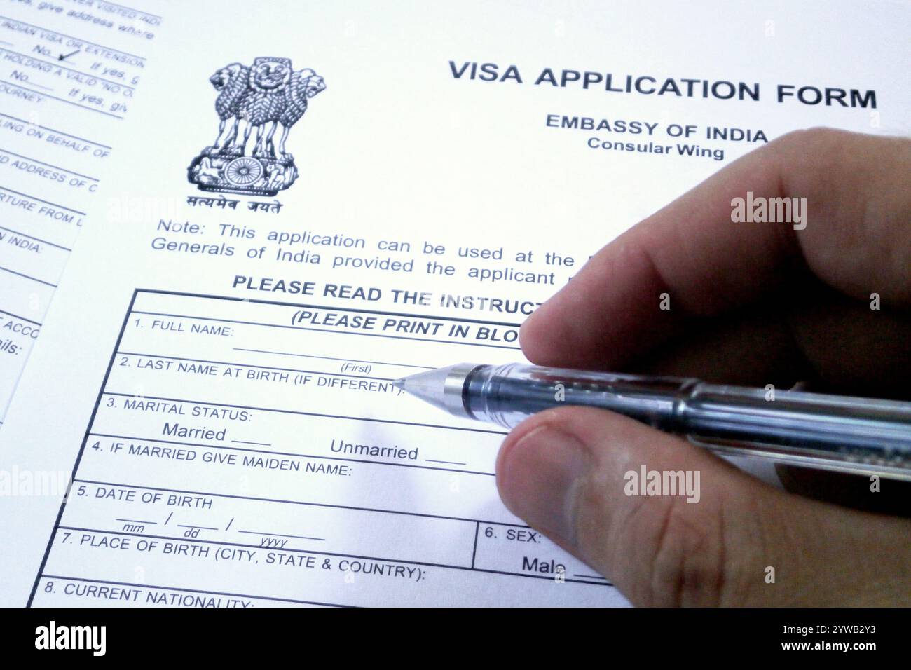 Ballpoint pen hold by the fingers of a man ready to fill a visa ...