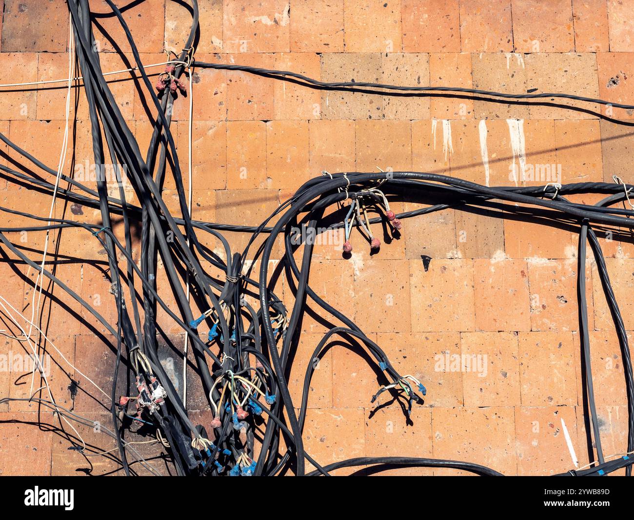 messy electrical cables and wires on outdoor wall of building covered ...