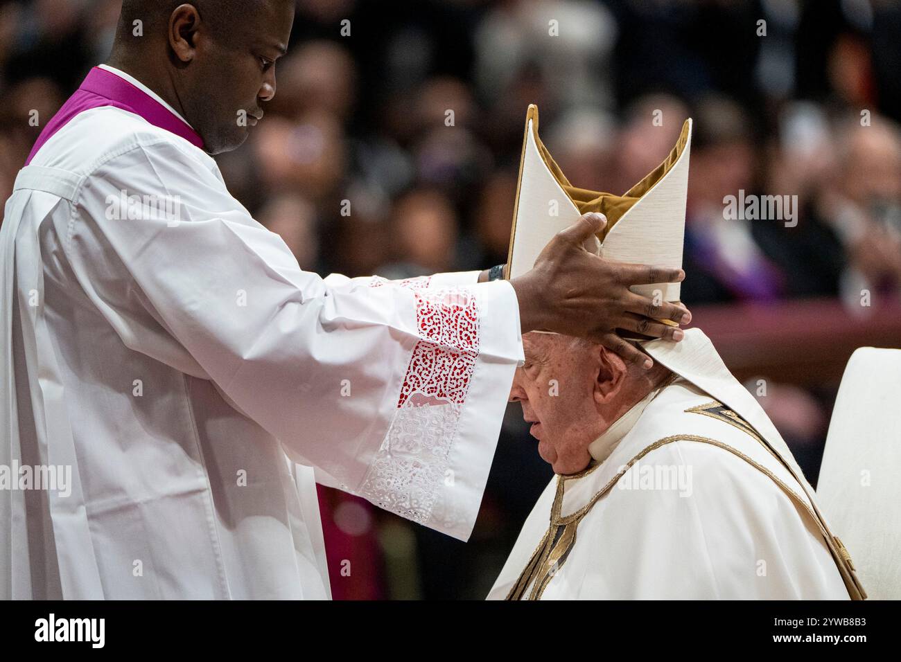 An assistant places the Mitre on the head of Pope Francis during the ...