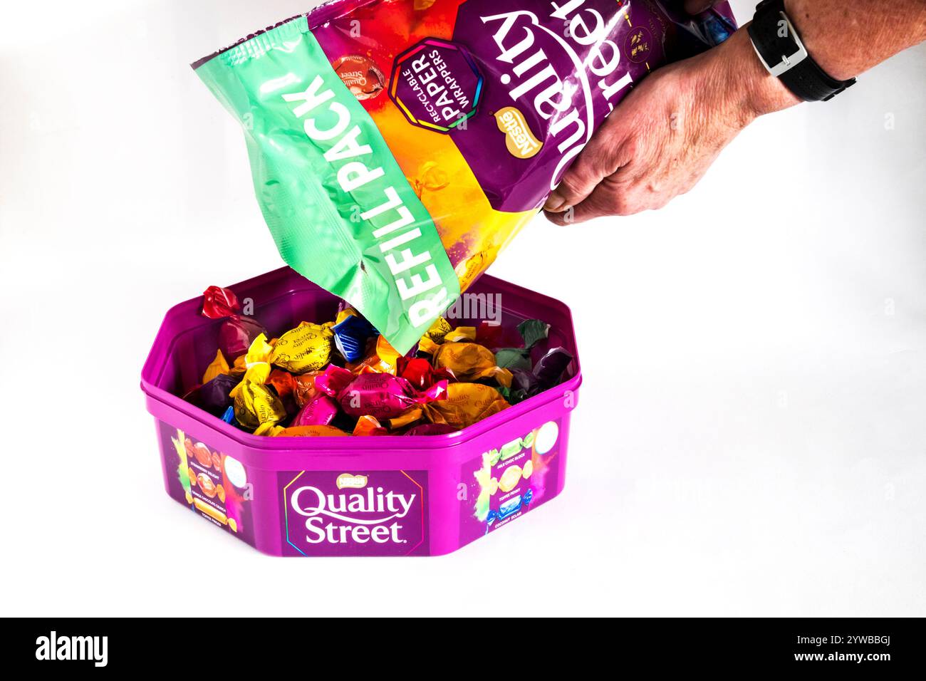Woman refilling a tub of Quality Street chocolates from a bulk refill ...