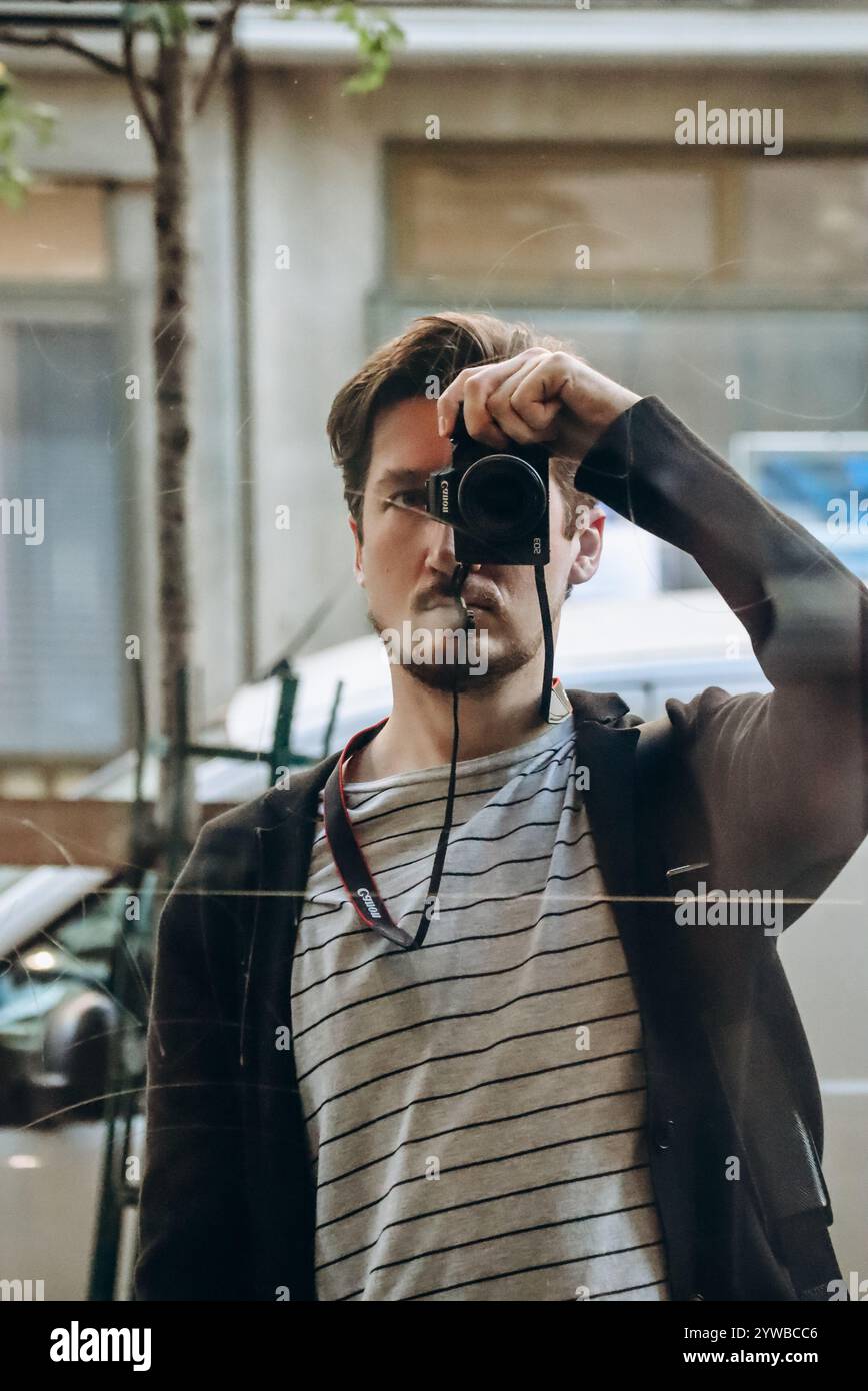 Photographer taking a selfie in the reflection of a storefront window ...