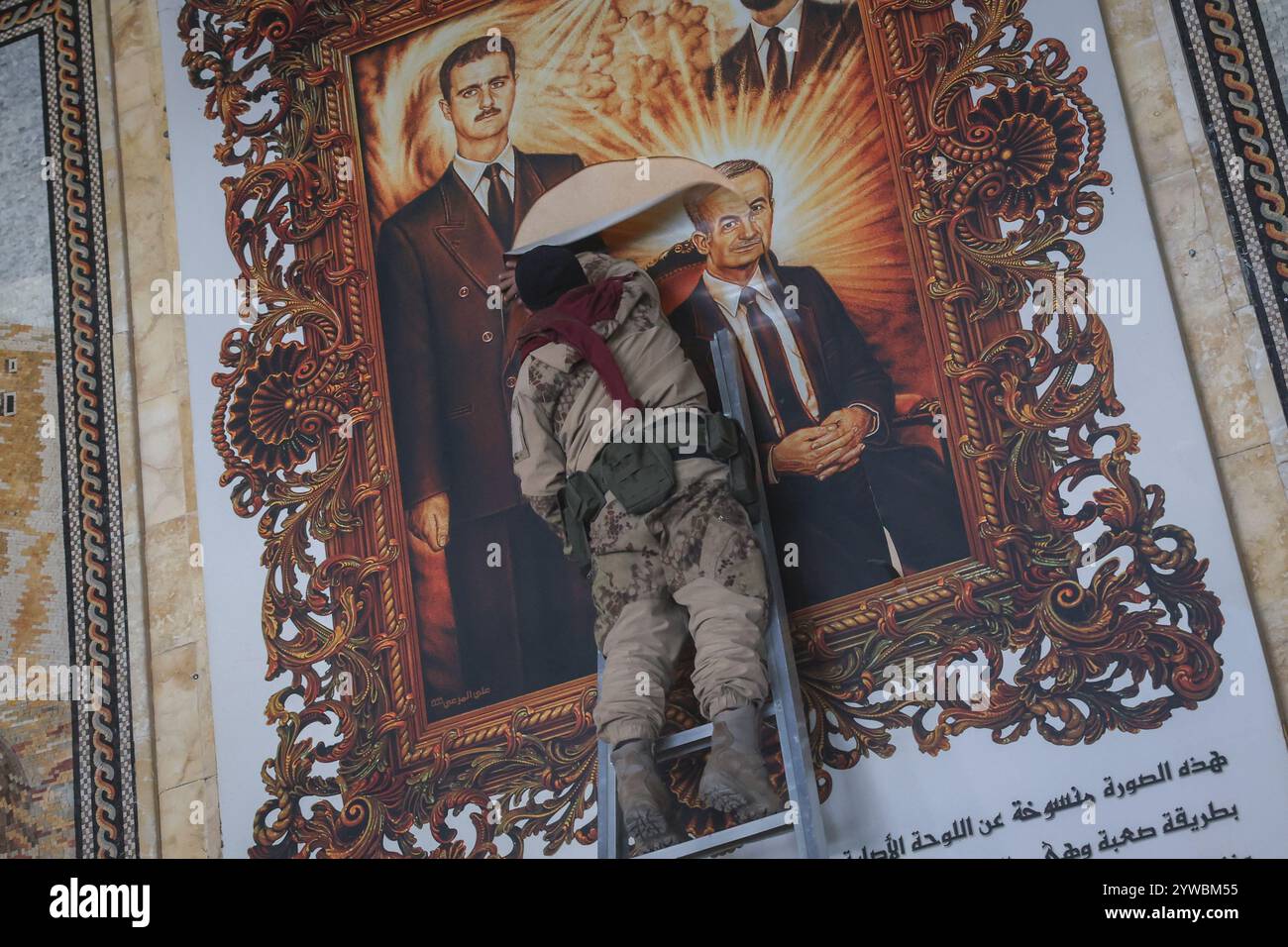 A Syrian opposition fighter tears a painting depicting Syria’s ...