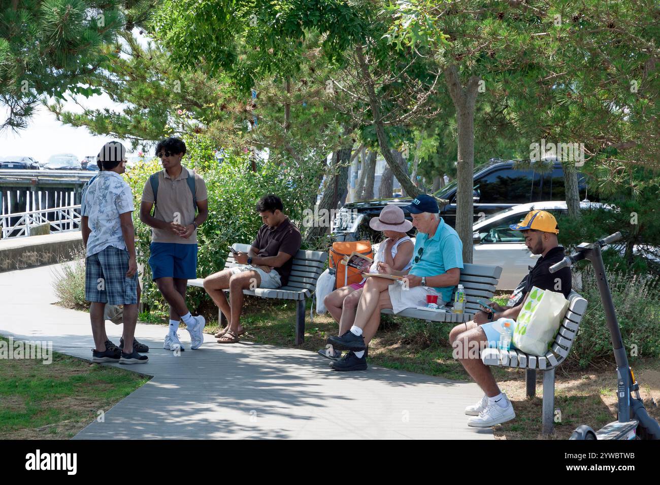 Mixed, diverse group of people talking while others are reading or on ...
