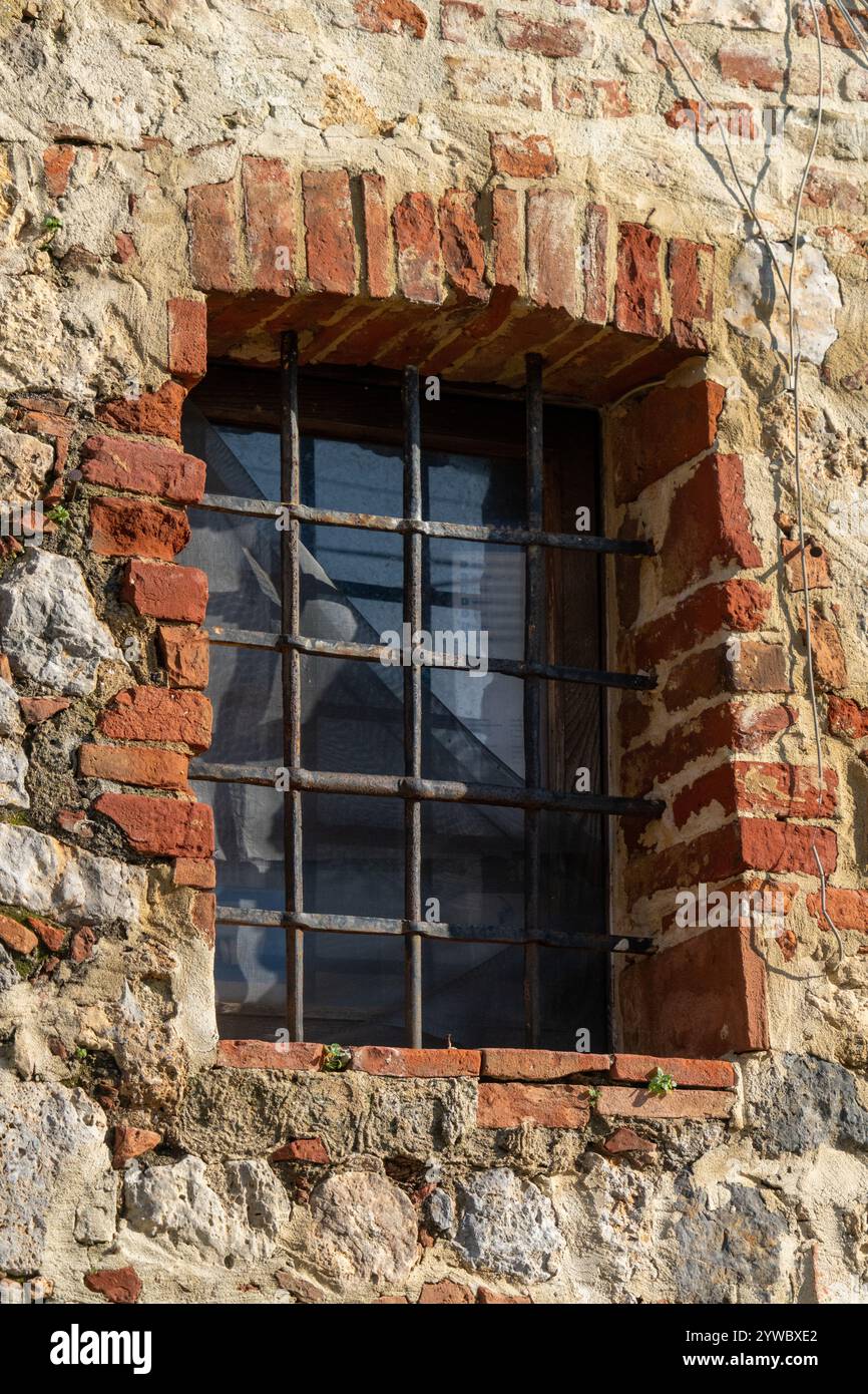 Barred window in a building in the medieval walled town of ...