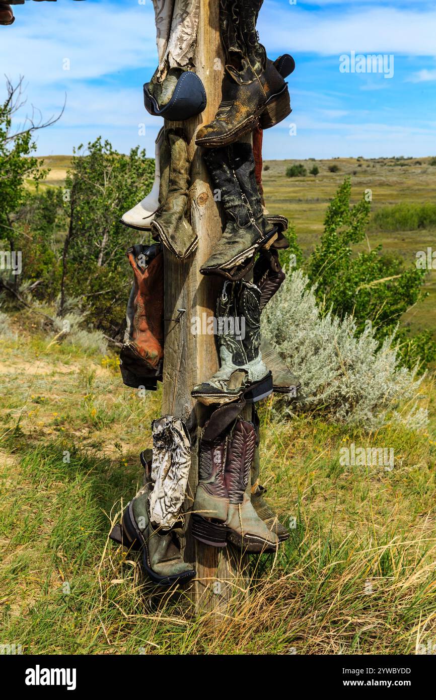 A pole with many cowboy boots on it. The boots are of different colors ...