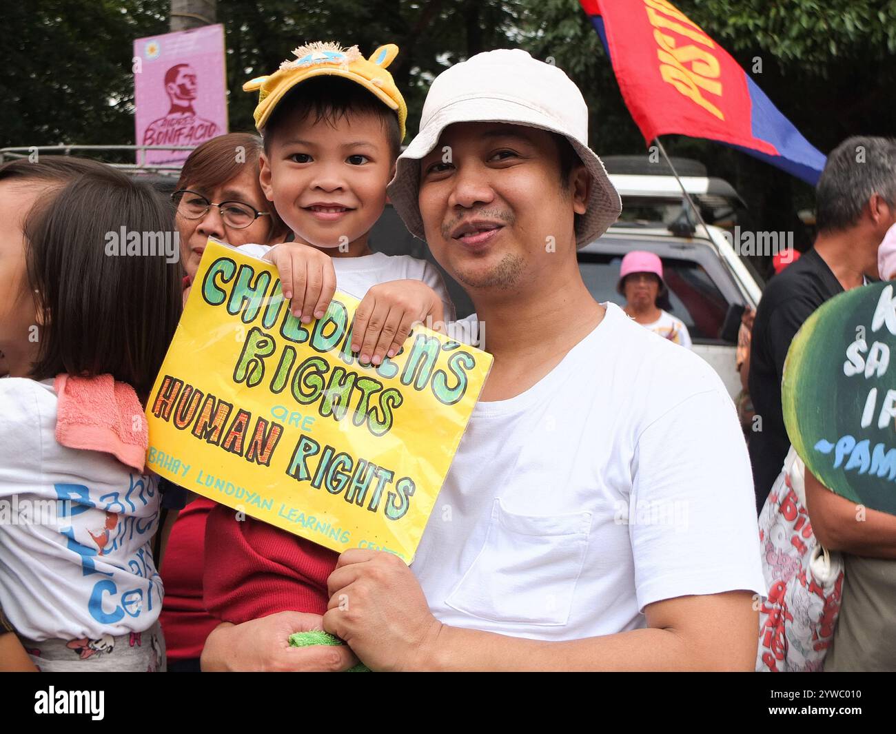A father and his son holding a placard with a message about children's ...