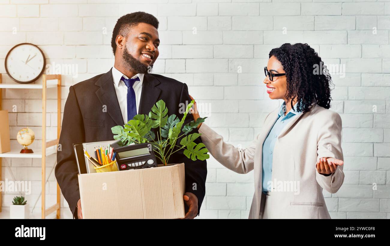 Joyful black guy with personal belongings being welcomed to work in ...