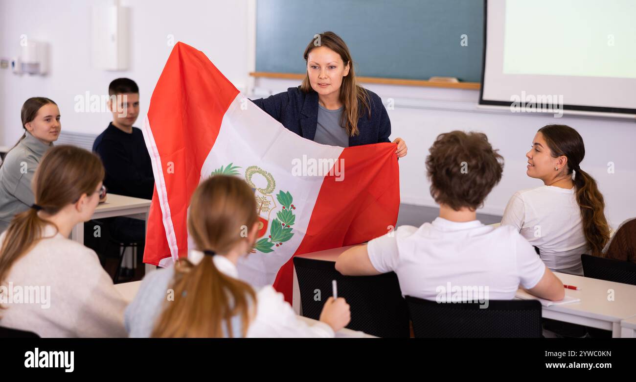 Teenage students in class and listening carefully to female teacher ...