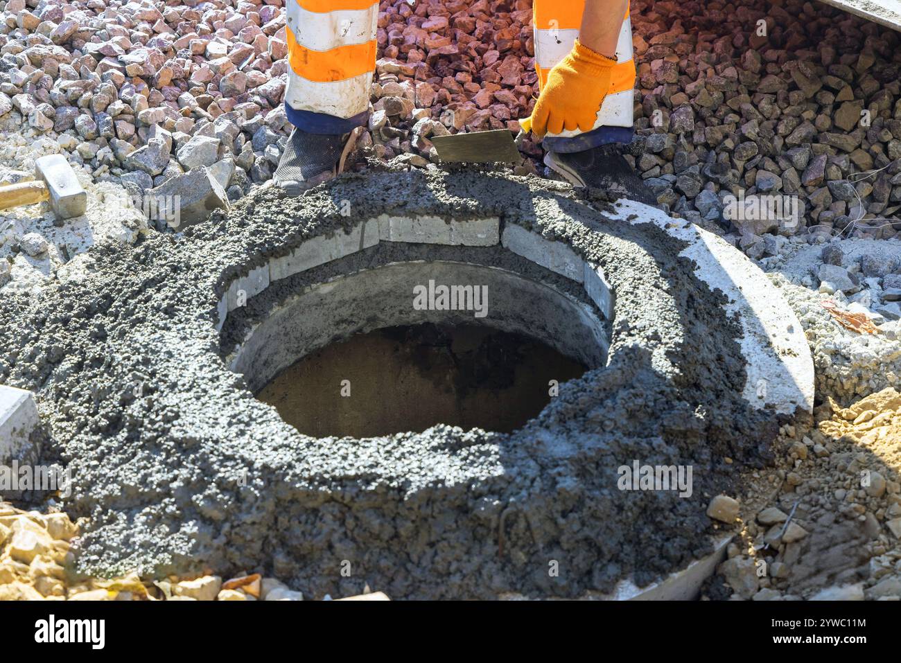Fresh concrete is being used to secure blocks at top of manhole for an ...