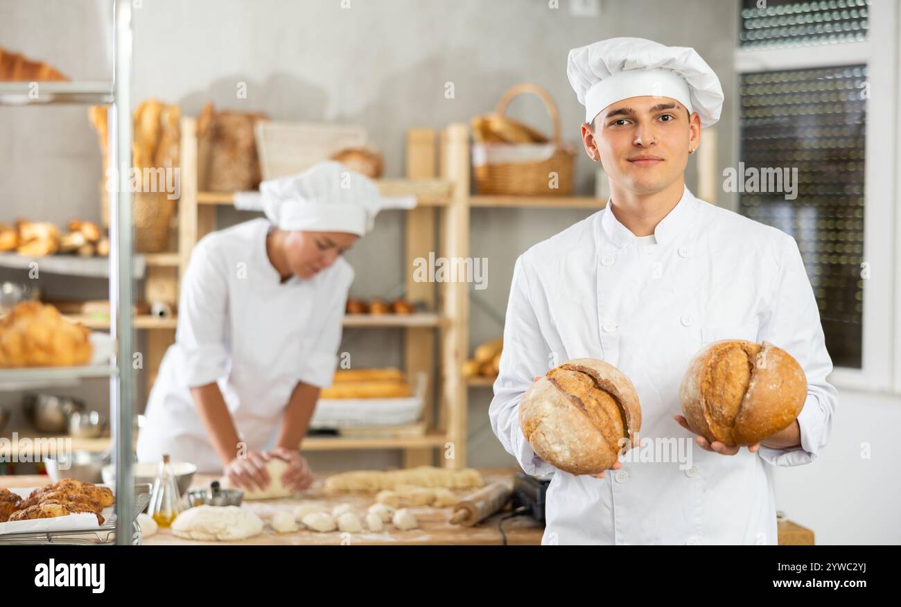 Bakery male employee holds ready made bread of bread in hands Stock ...